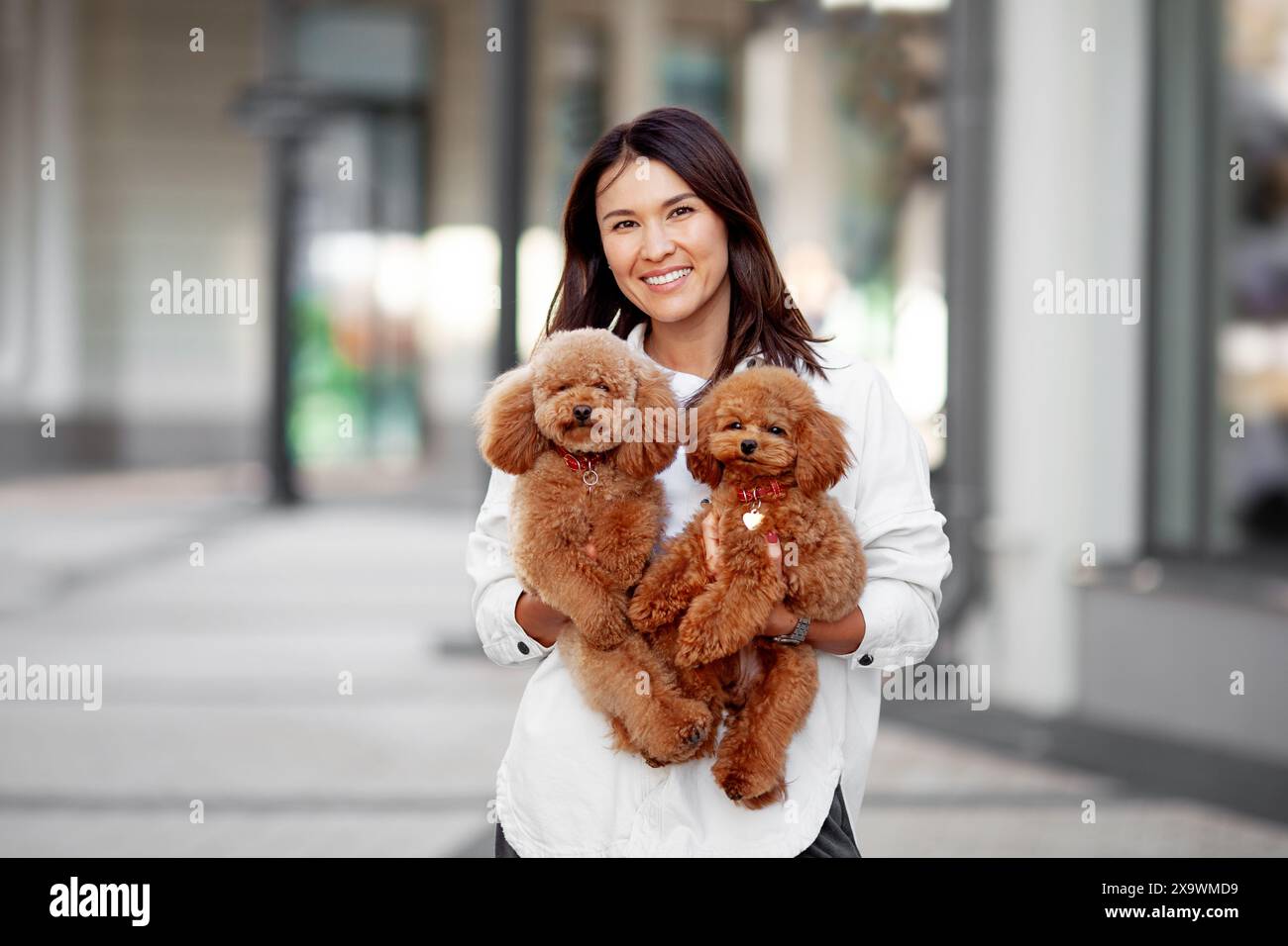 Cheerful woman with long dark hair holds two adorable brown dogs ...