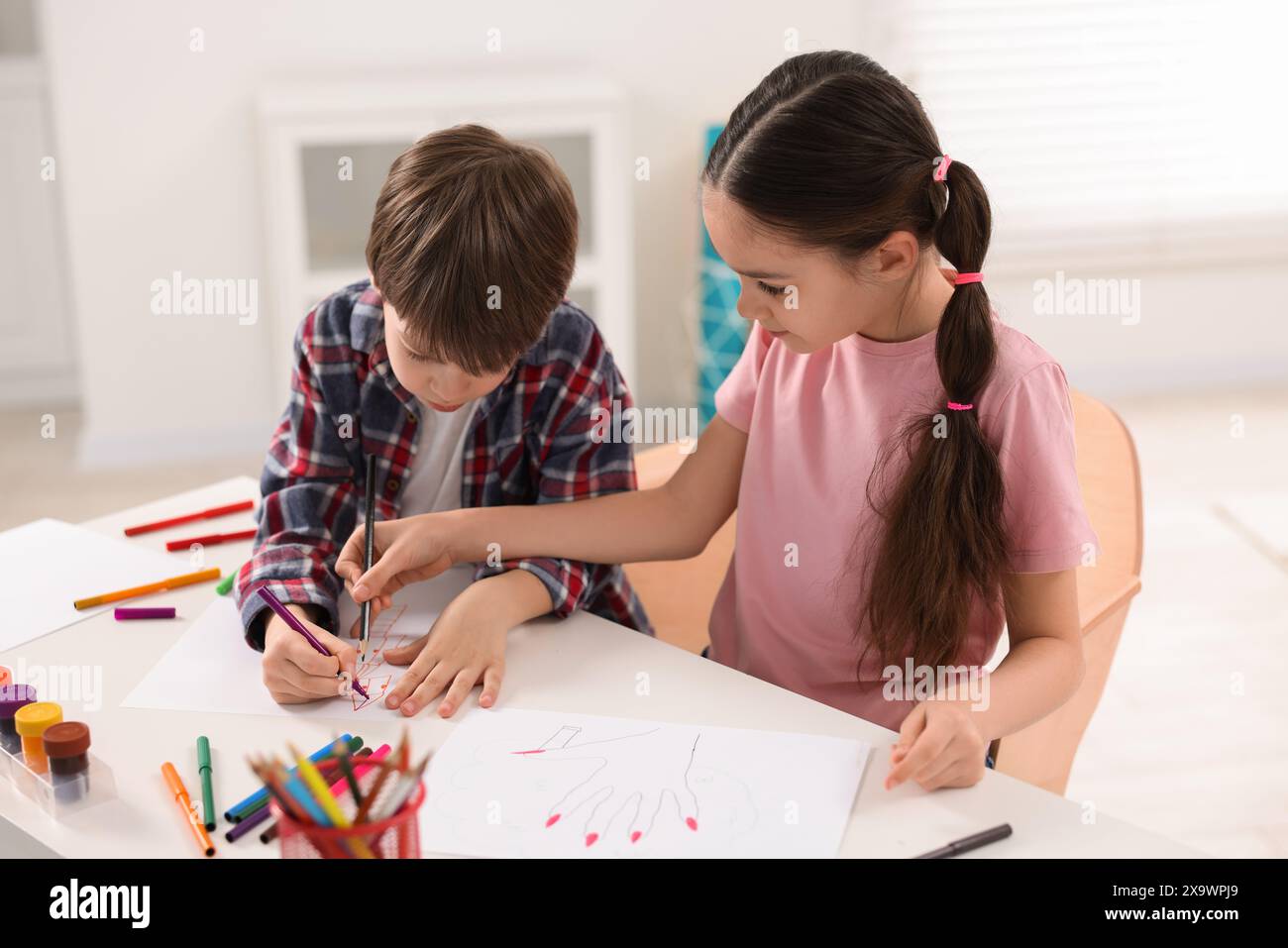Happy brother and sister drawing at white table in room Stock Photo - Alamy