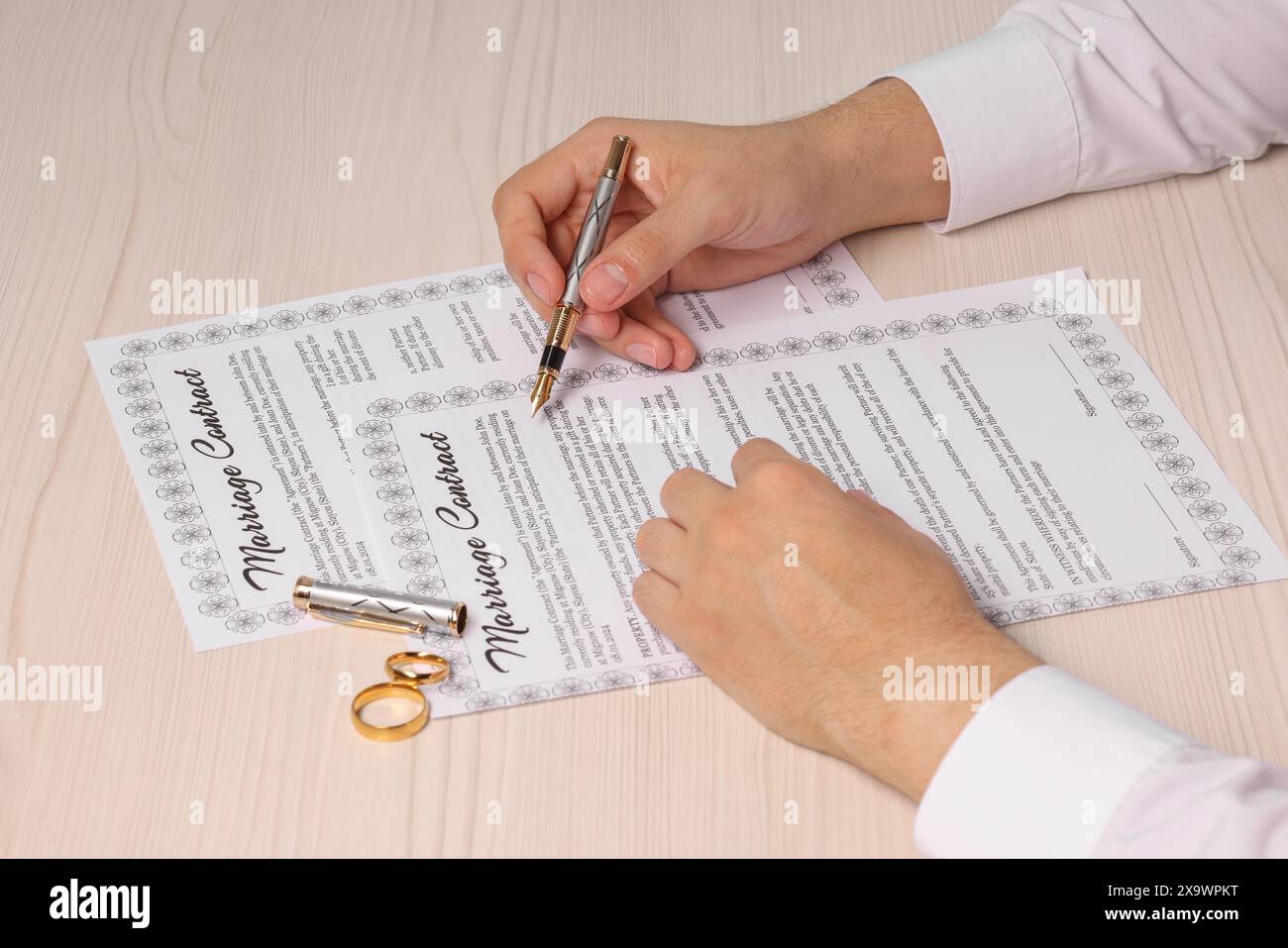 Man signing marriage contract at light wooden table, closeup Stock ...
