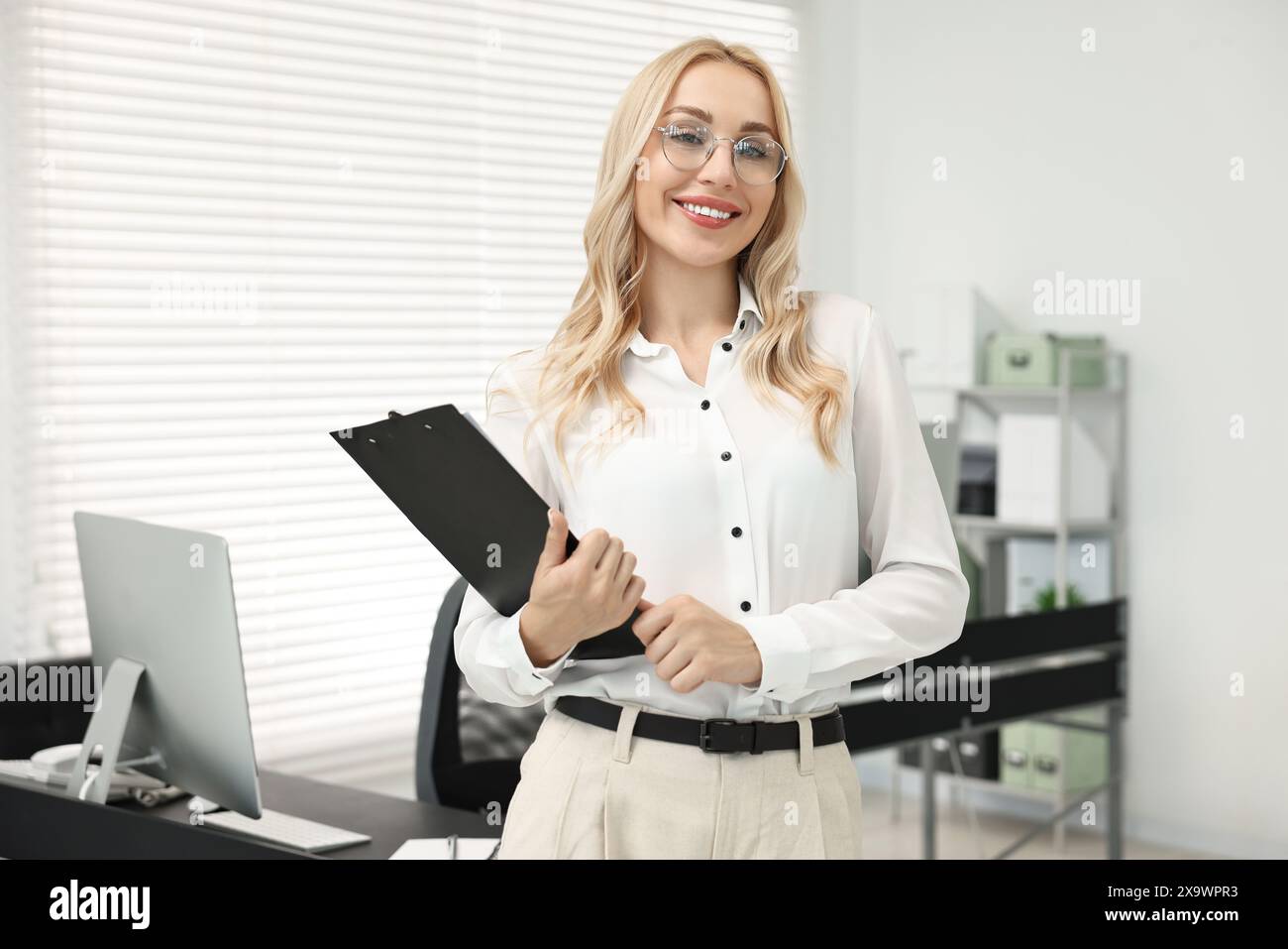 Happy secretary with glasses and clipboard in office Stock Photo - Alamy