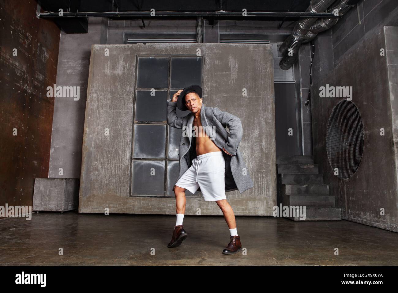 Male dancer, wearing gray coat, white shorts and black hat, performs in ...