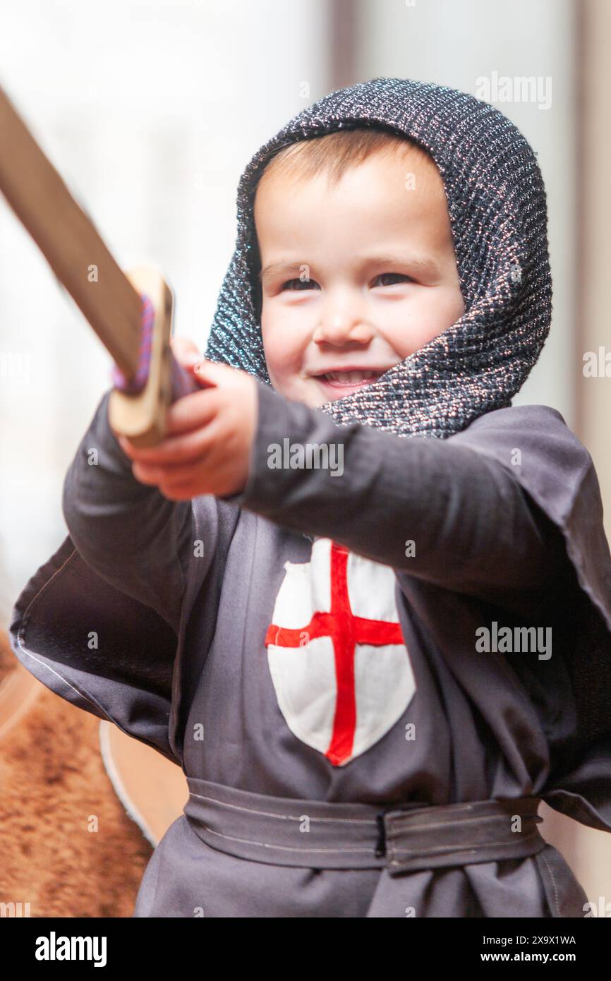 Toddler in knight costume with big smile playing with sword. Learning ...