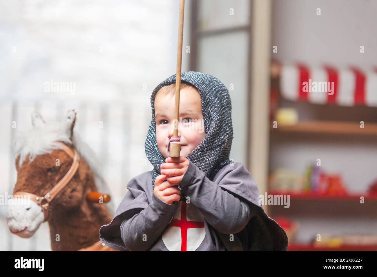 Toddler dressed as a knight with sword in a playroom. Play, education ...