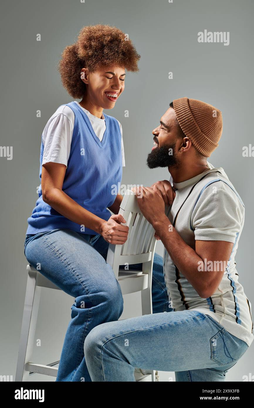 An African American man and woman dressed stylishly, sitting on stools ...