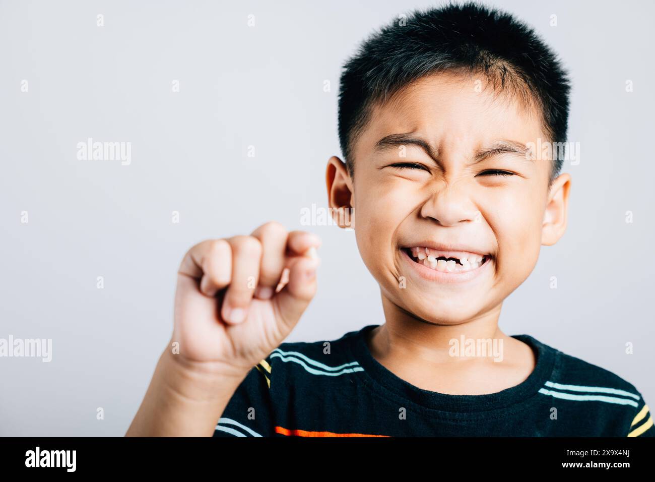 Hand of a happy boy holds a fallen baby tooth denoting dental hygiene ...