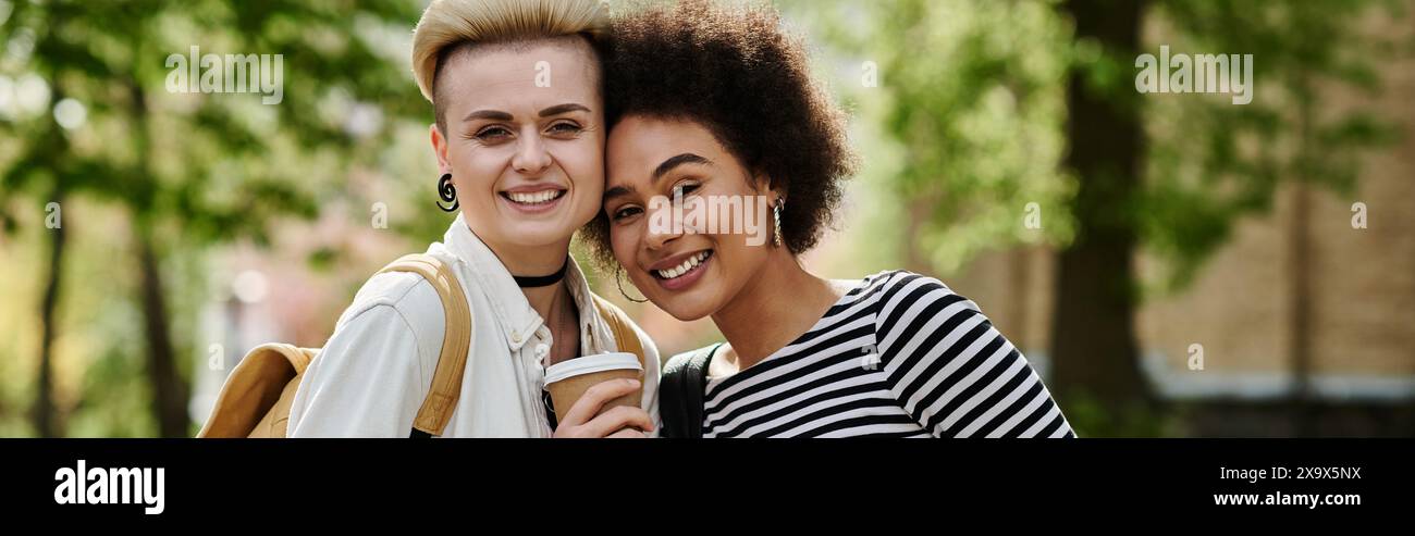 Two young women in a park share a happy moment, smiling at each other ...