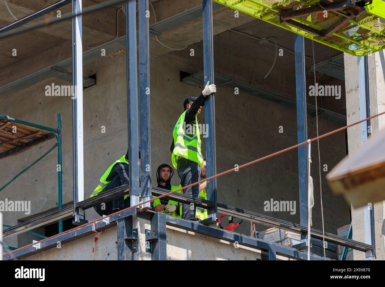 Male construction workers are installing the iron frame for the glazing ...