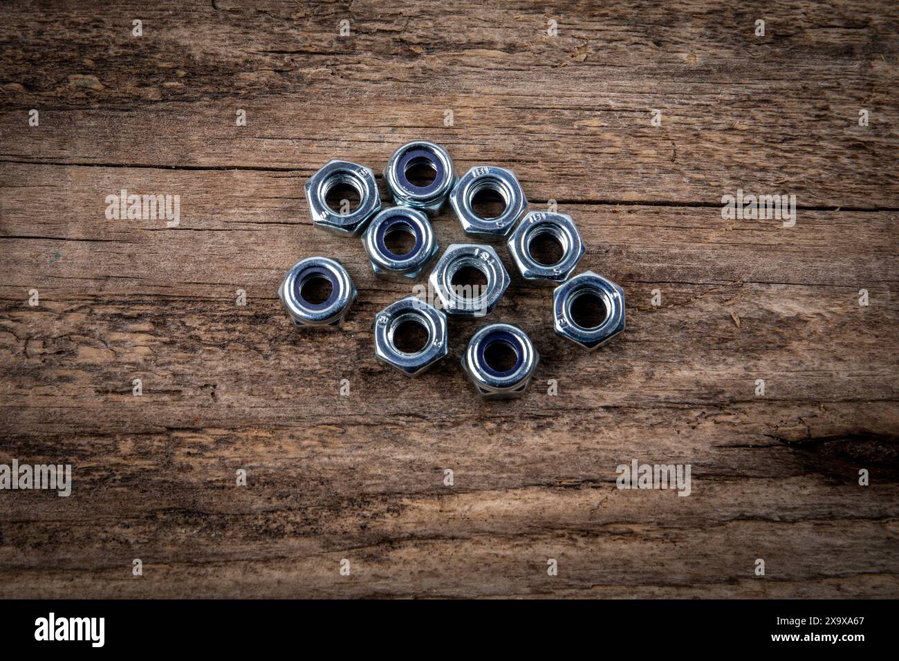 Stack of zinc plated self locking hexagon nuts on a dark wood texture ...