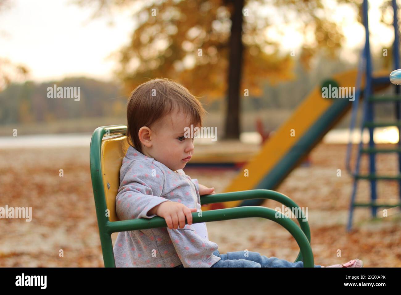 Little beautiful girl rides on a carousel in the autumn park. The ...