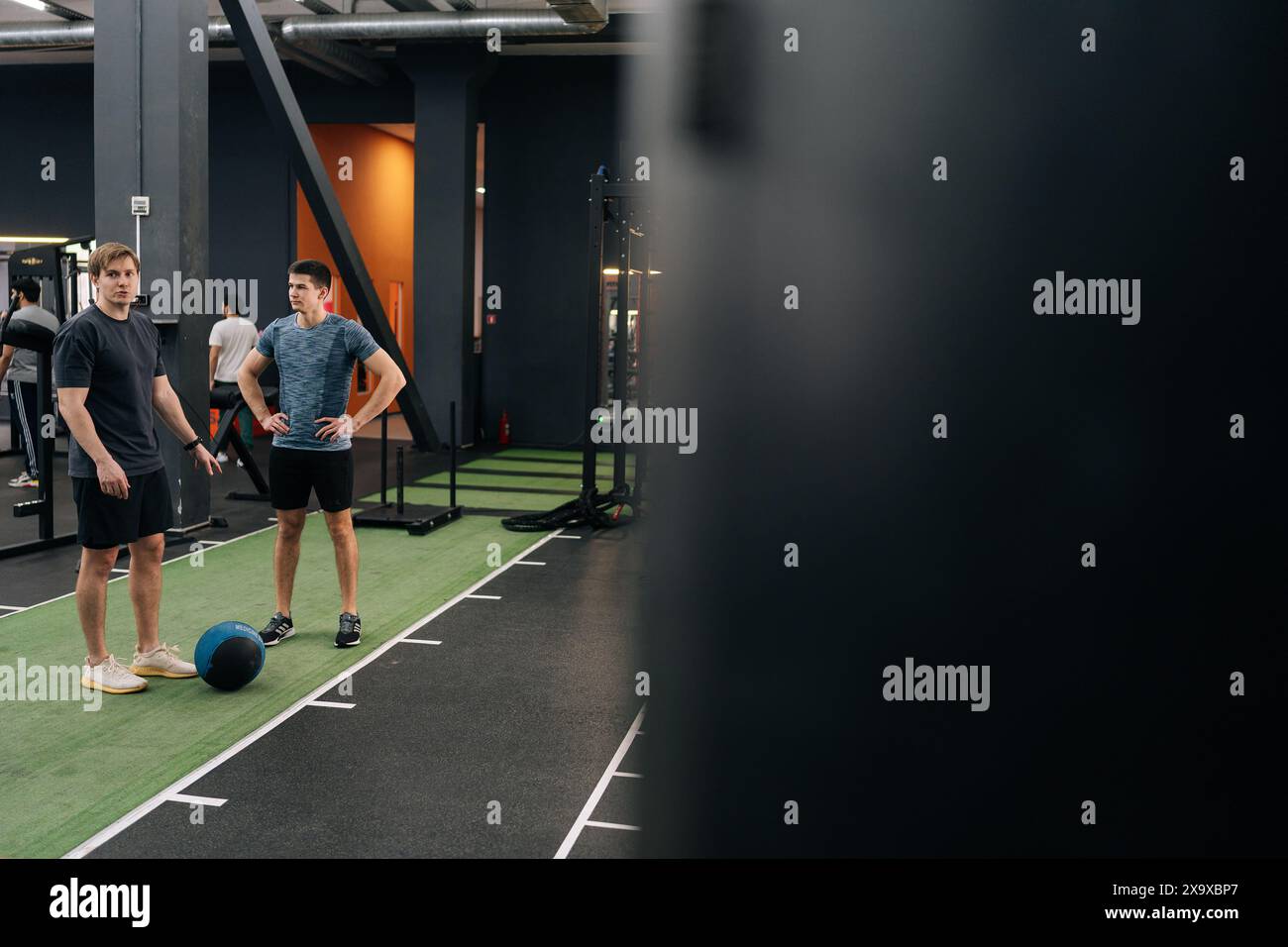 Remote wide shot of personal trainer explaining correct execution of ...