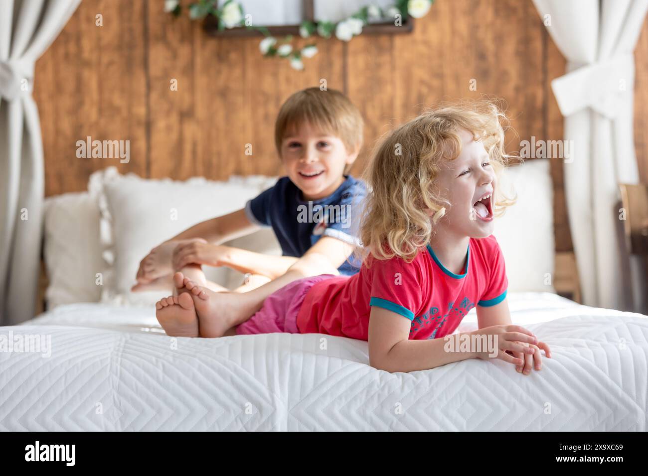 Cute sweet toddler children, tickling feet on the bed, laughing and ...