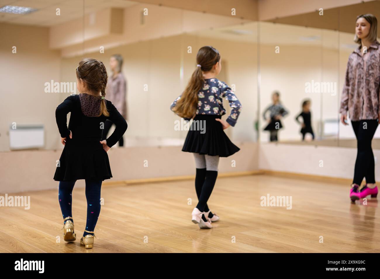 Two young girls learning dance in a studio, guided by their female ...