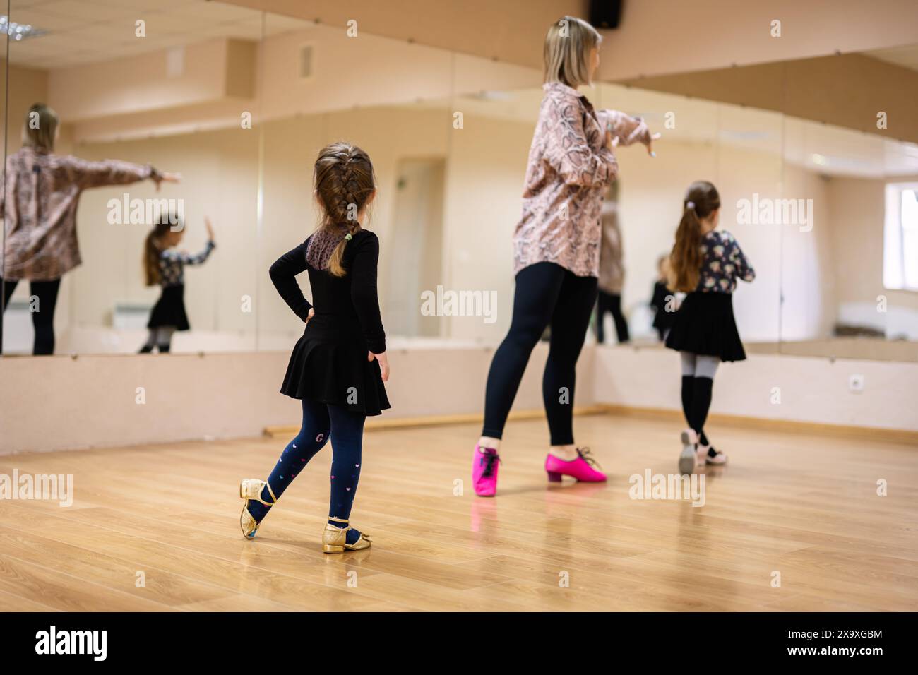 Two young girls learning dance steps with their instructor in a ...