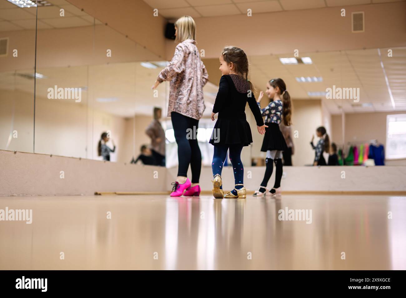 Children practicing dance moves with an instructor in a ballet studio ...