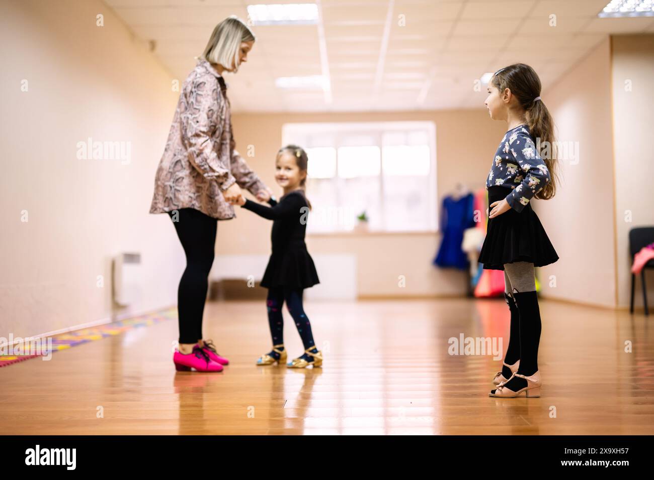 A dance instructor teaches two young girls in a bright and spacious ...