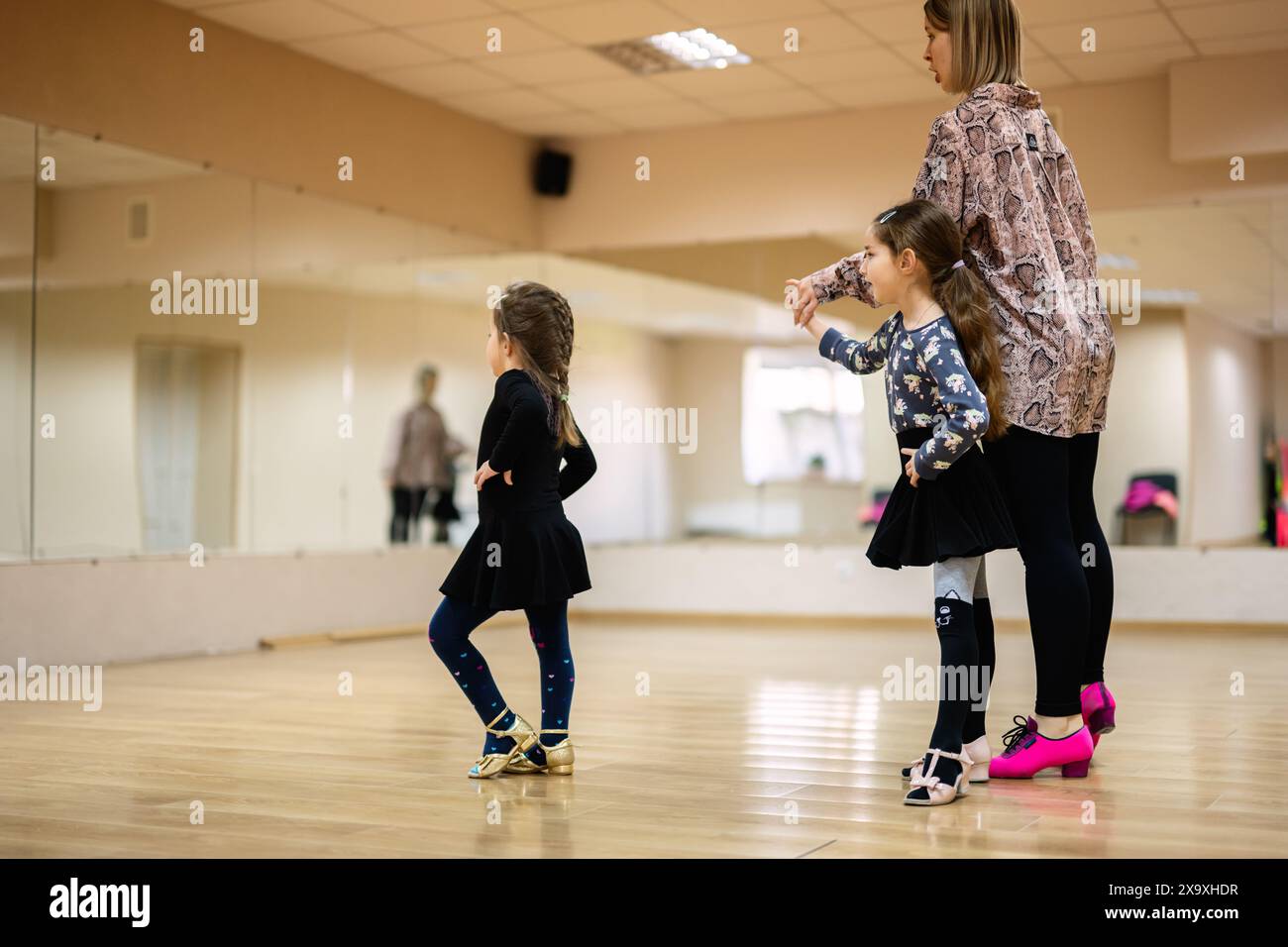 Two young girls practice dance moves guided by their instructor in a ...