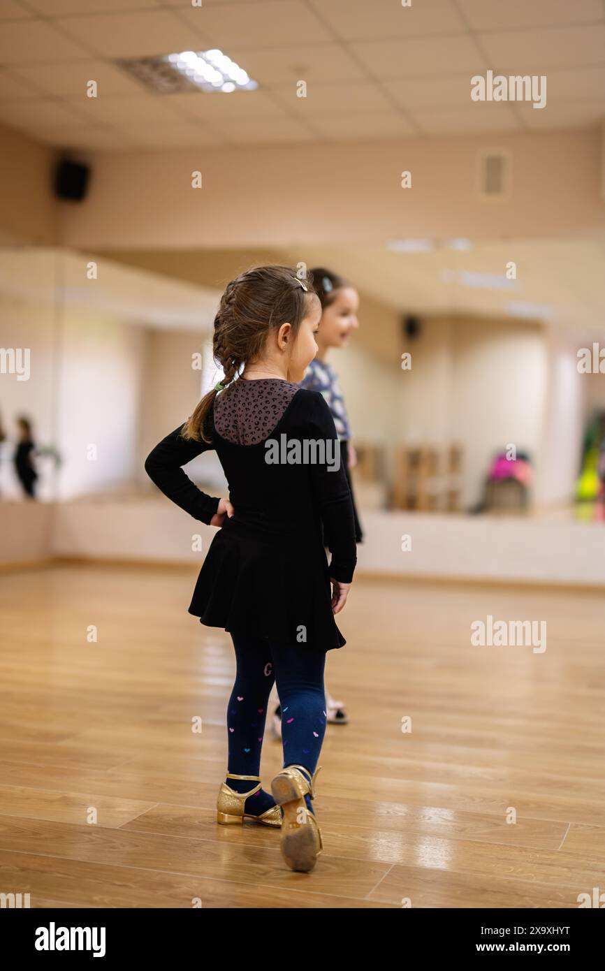 Two young girls participating in a dance class in a studio with a ...