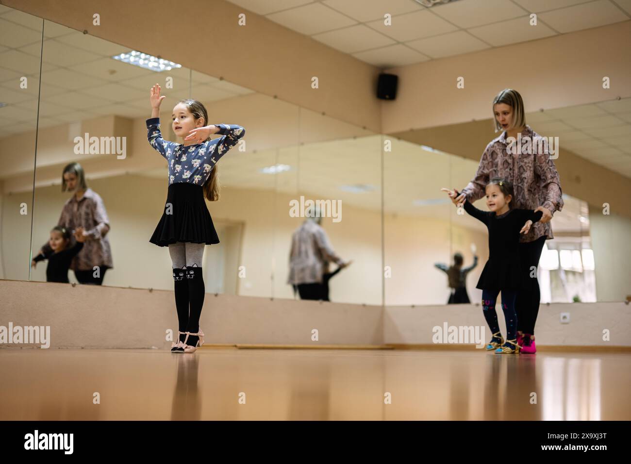 Two young girls learning ballet with a female instructor in a dance ...