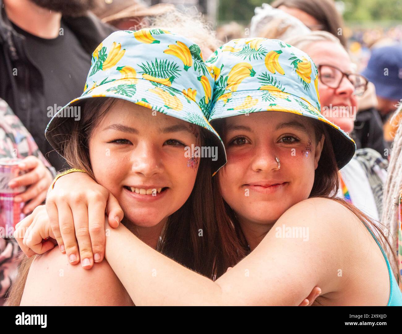 Two young festival goers having fun and hugging for the camera at the ...