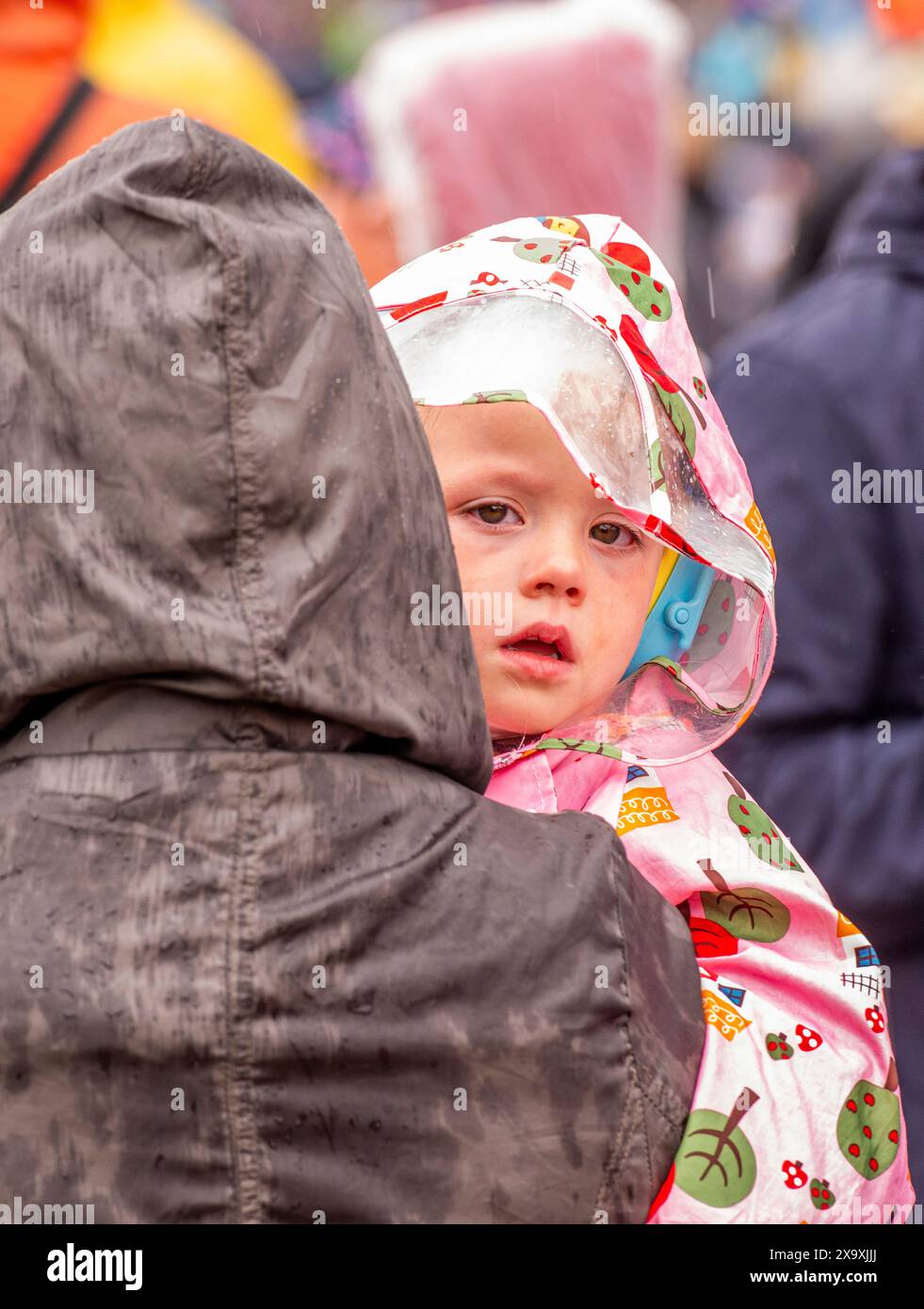 A baby is held by his dad while sheltering from the heavy rain at the ...