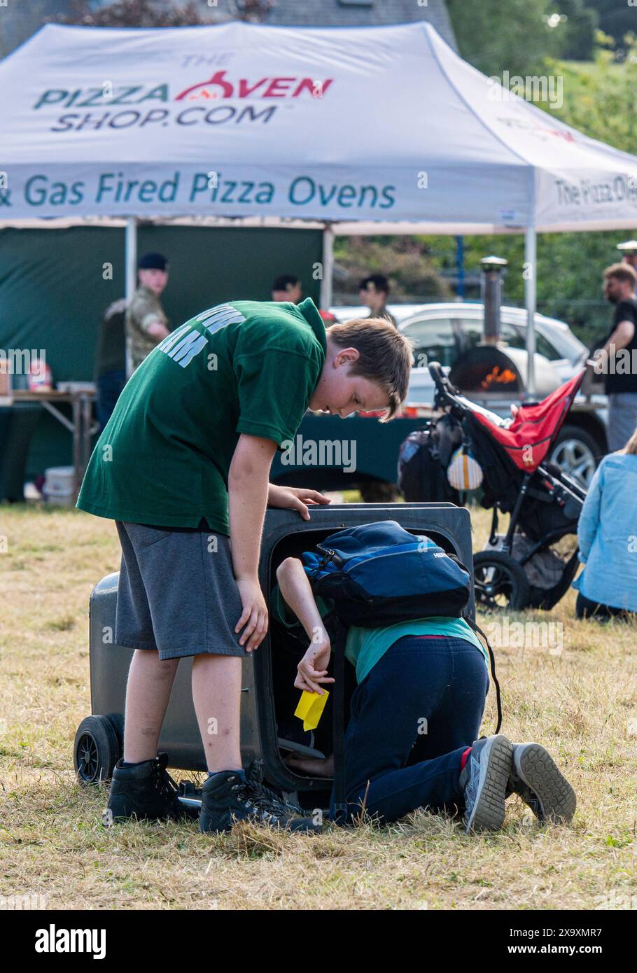 Two boys are looking for something in a dustbin with one of them ...