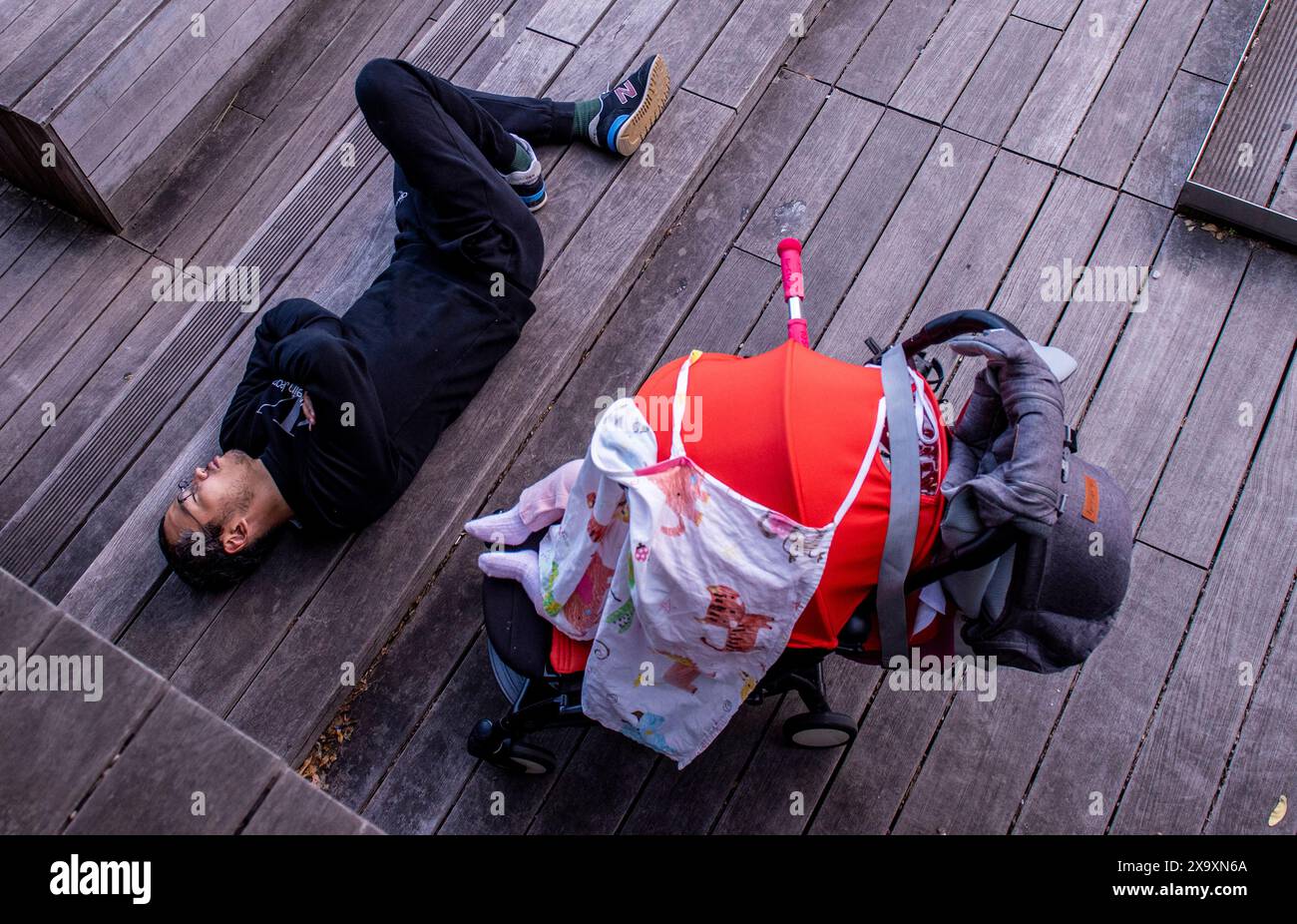 A man is asleep on a wooden decking in Downtown Manhattan in New York ...