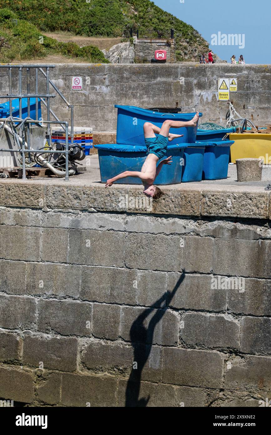 A young male teenager making an acrobatic jump into the sea at Newquay ...