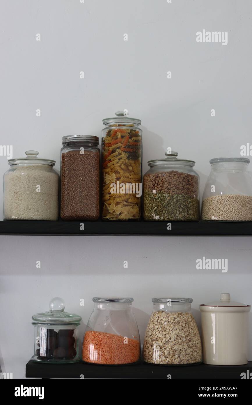 Stocked kitchen pantry. Shelves with different cereals in jars on white ...