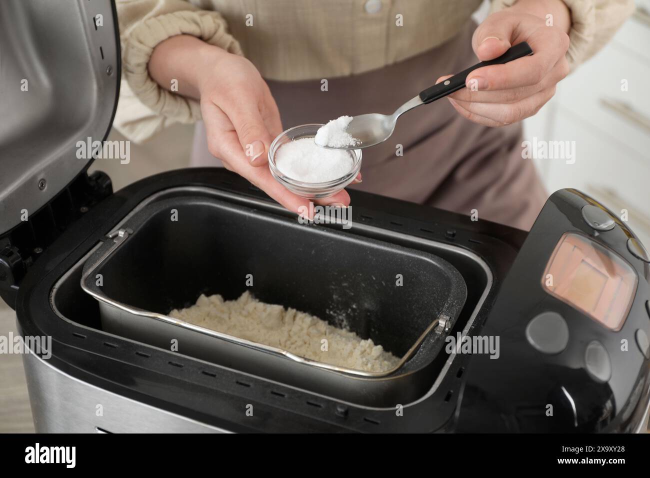 Making dough. Woman adding salt into breadmaker machine, closeup Stock ...