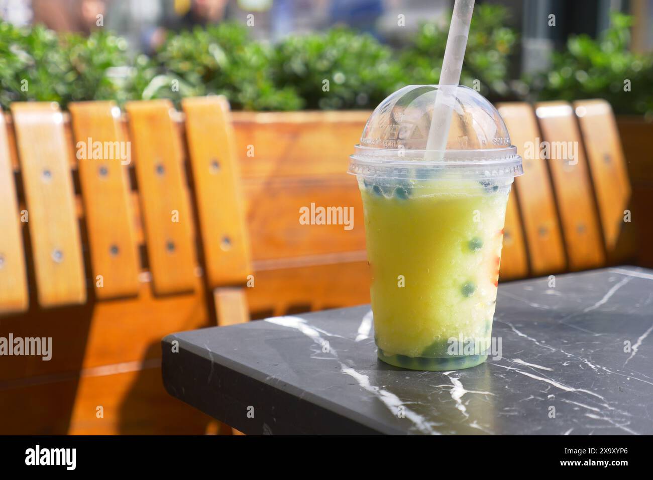 Refreshing yellow bubble tea with tapioca pearls sits on a marble table ...