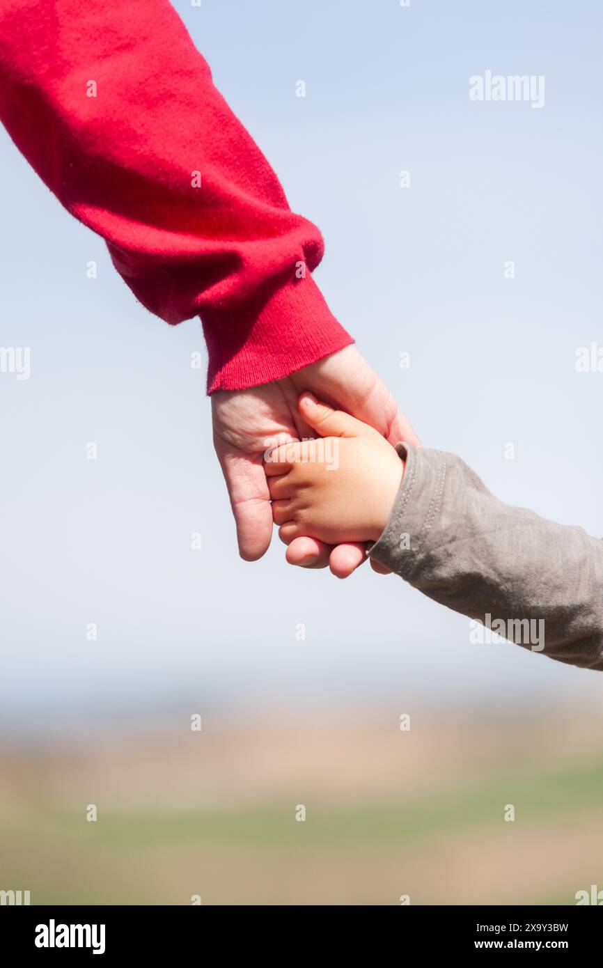 Close-up of mother and child holding hands, accompaniment, priest ...