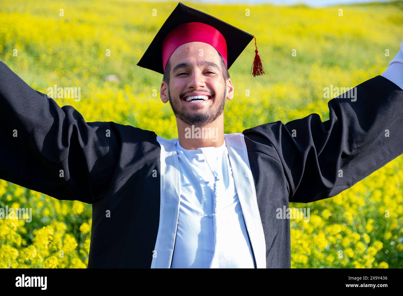 Cheerful young arab male wearing kandora and celebrating his graduation ...