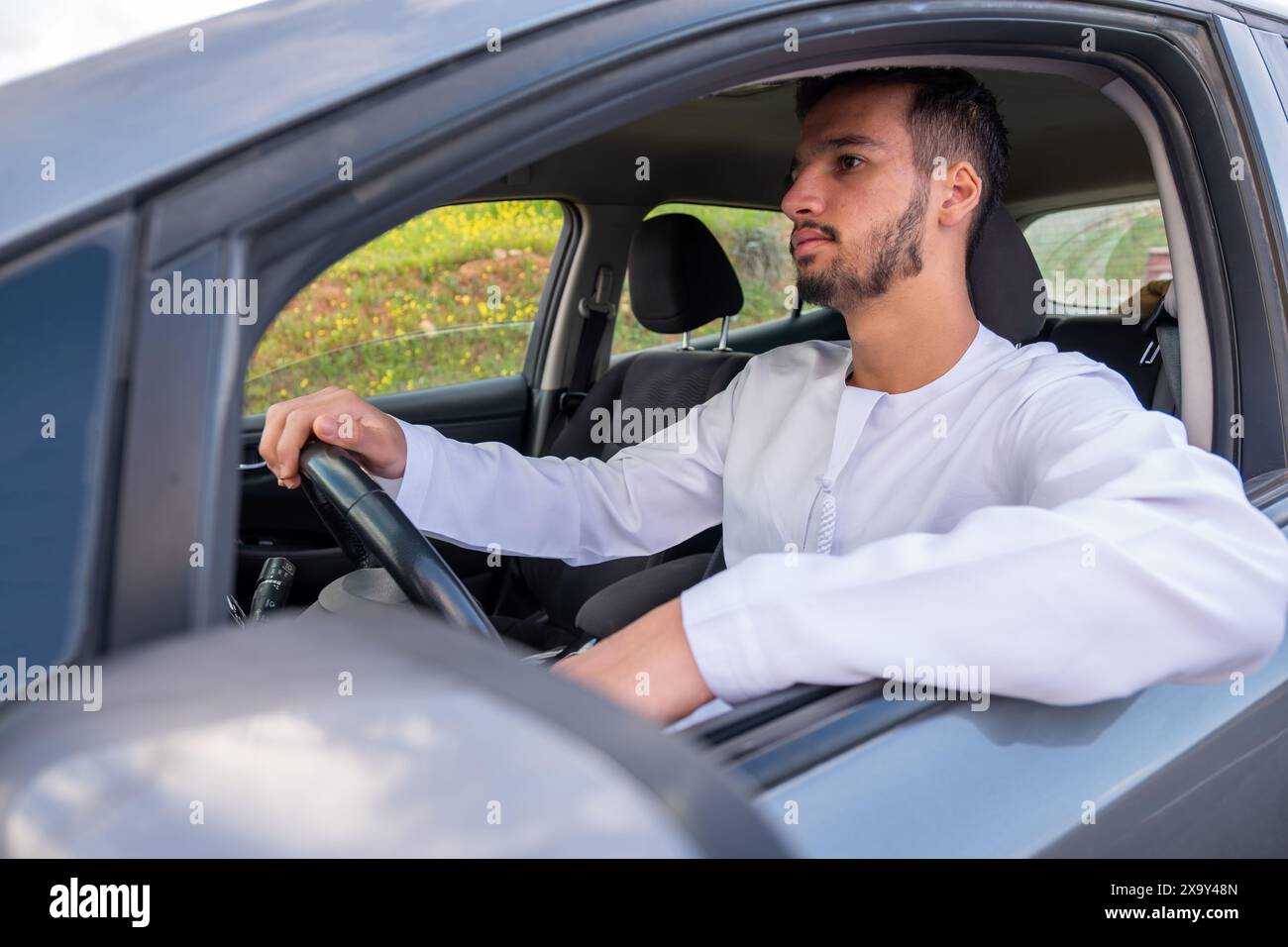 A cheerful young man with a beard, wearing a traditional Middle-Eastern ...