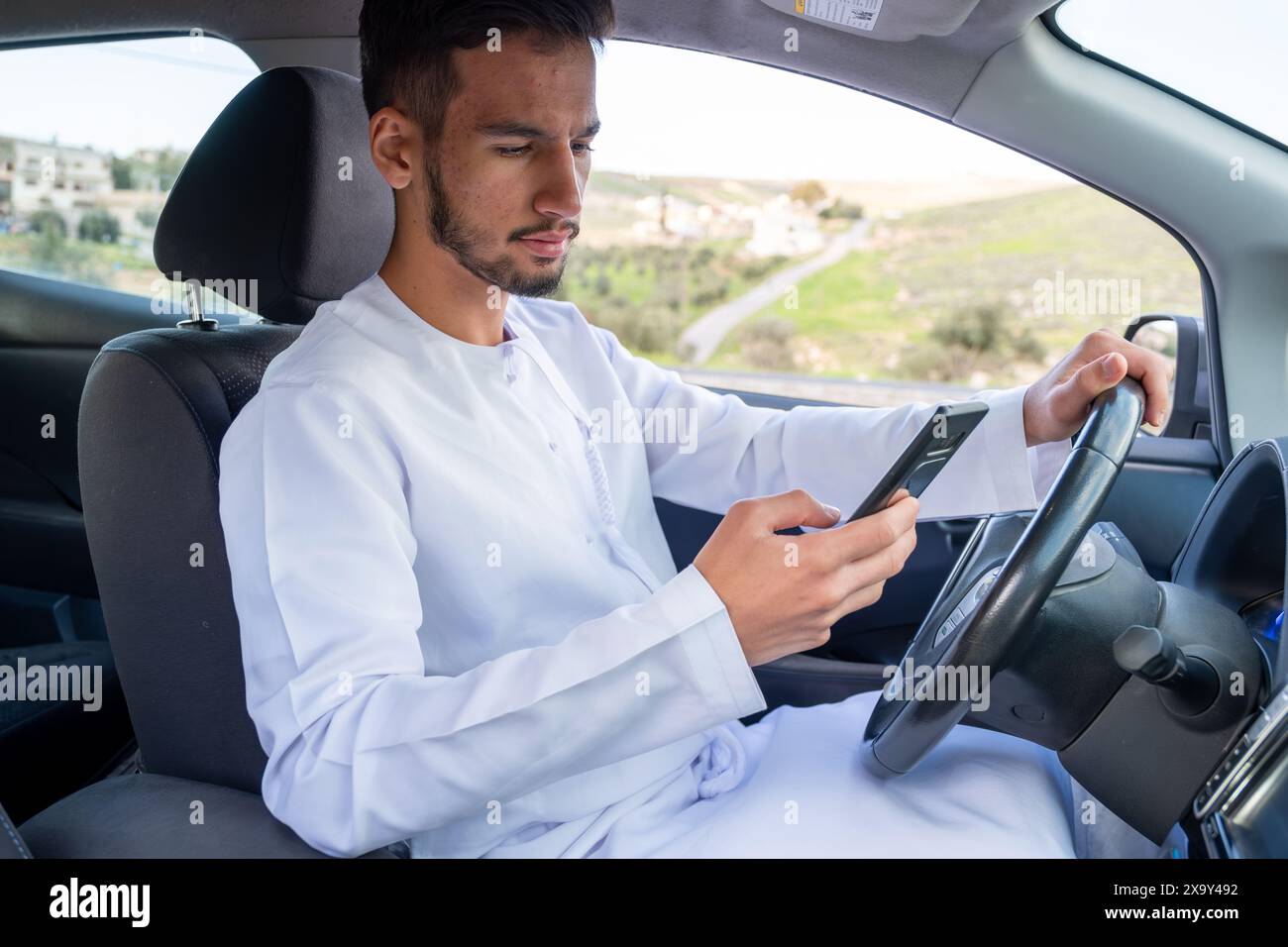Young arab male using mobile phone while driving Stock Photo - Alamy