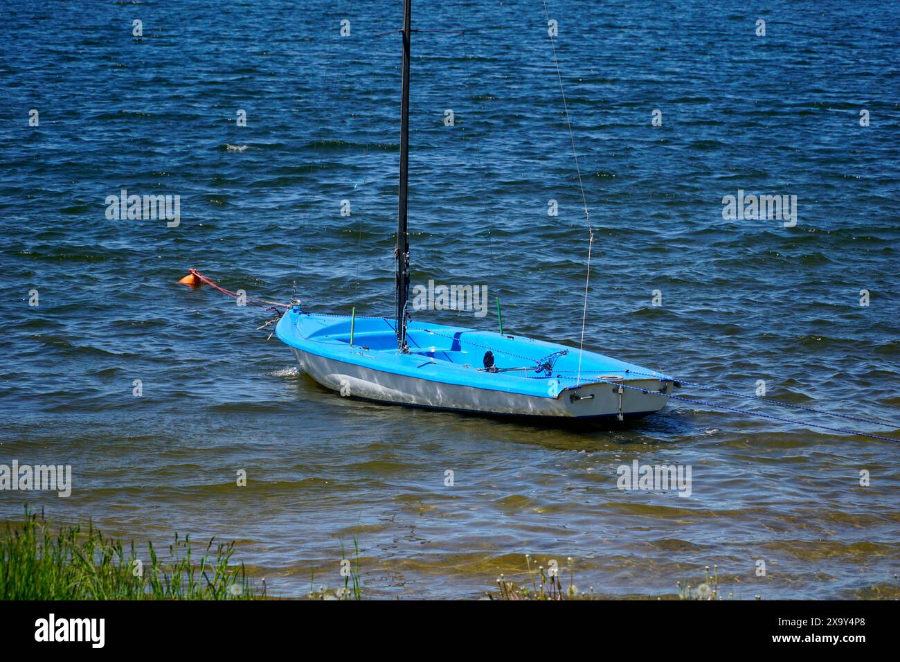 Blue yacht without sails at lake shore Stock Photo - Alamy