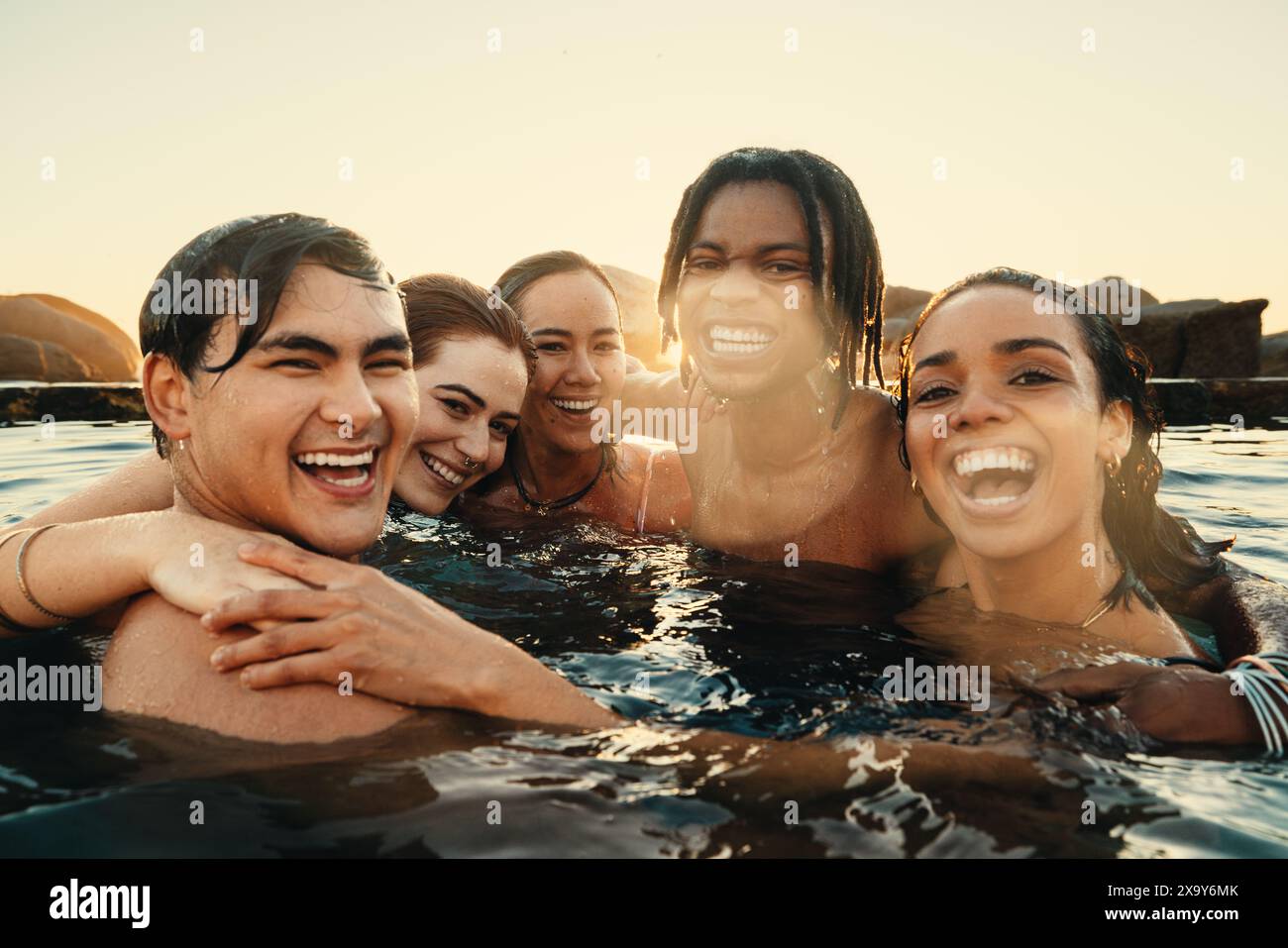 Group of best friends having fun abroad in a swimming pool at sunset ...