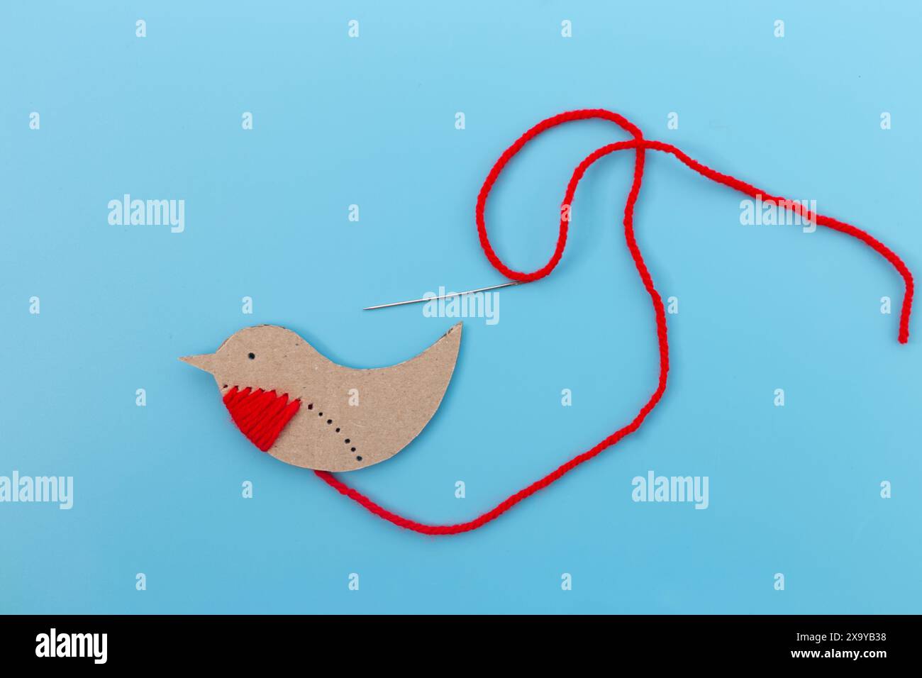 a craft project in progress, hand-sewn light brown cardboard bird with ...