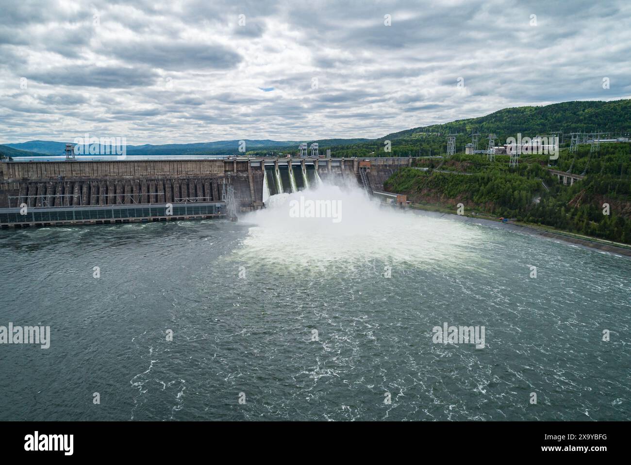 Aerial view of concrete dam releasing water into river on cloudy day ...