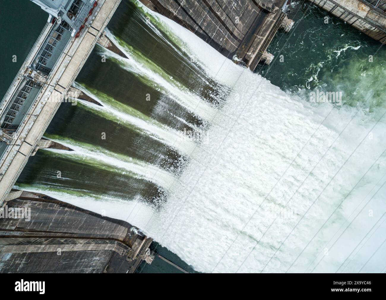 Aerial top down view of concrete dam releasing water into river on ...