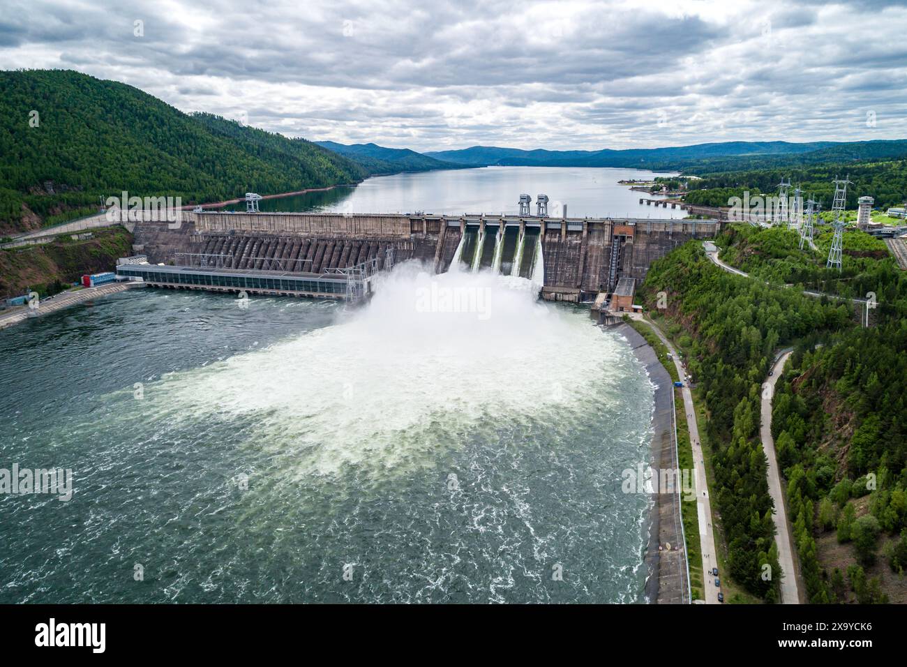 Aerial view of concrete dam releasing water into river on cloudy day ...