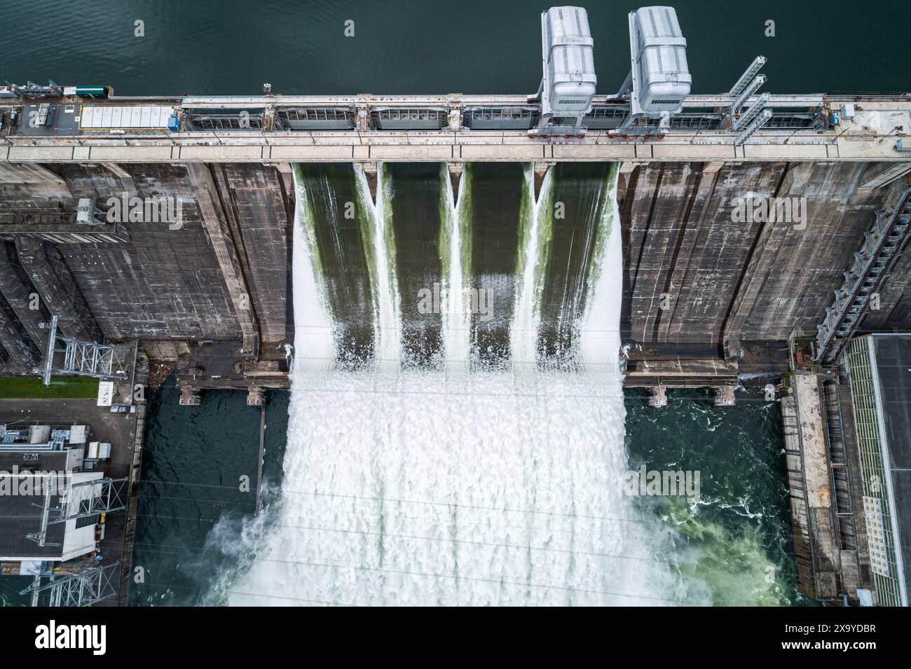 Aerial top down view of concrete dam releasing water into river on ...