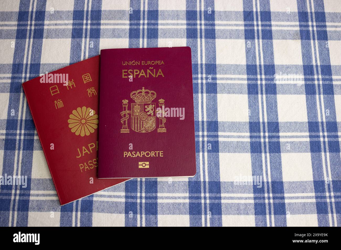 A Japanese and a Spanish passports placed side by side on a cloth ...