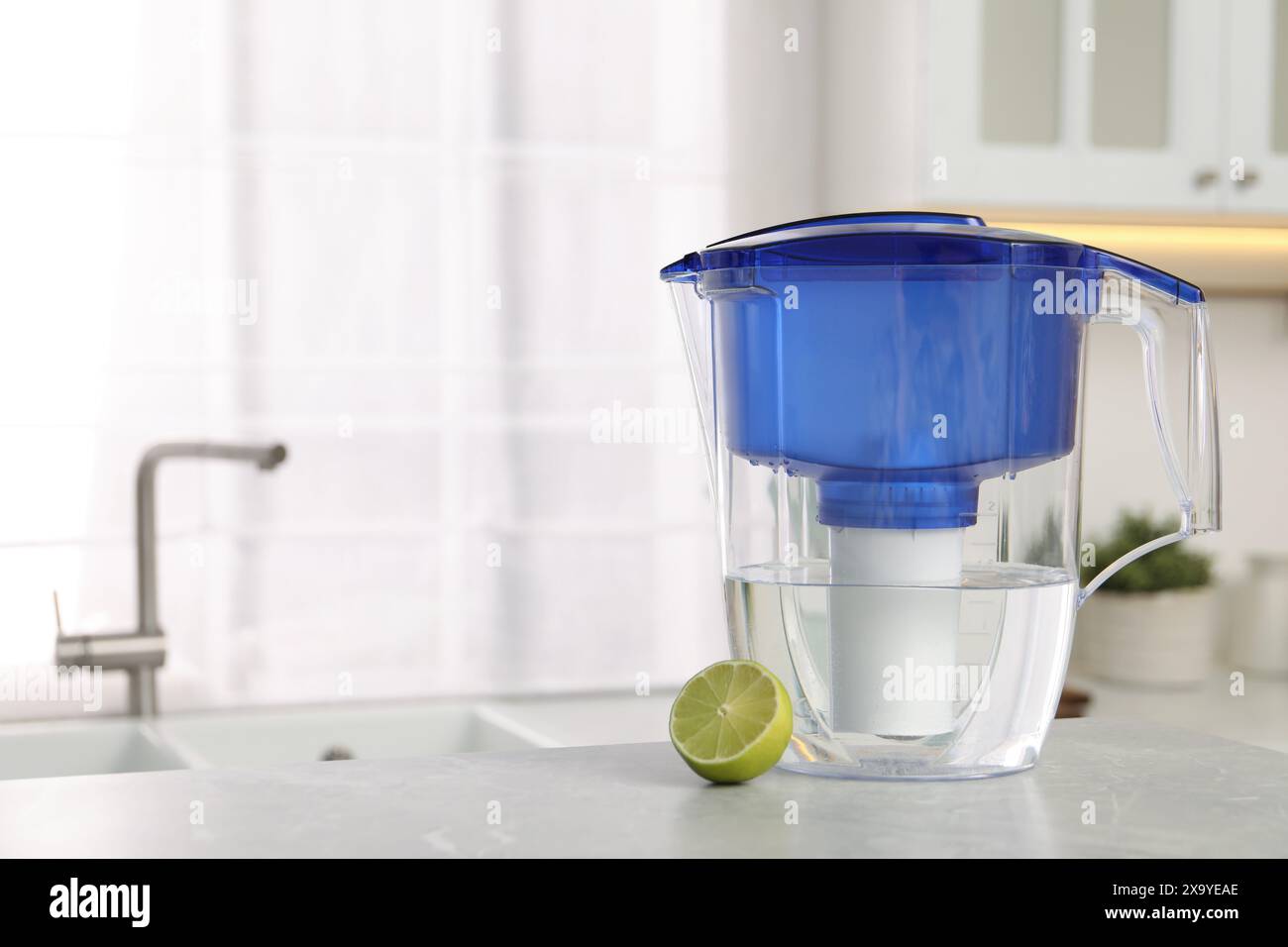 Water filter jug and lime on light table in kitchen. Space for text ...