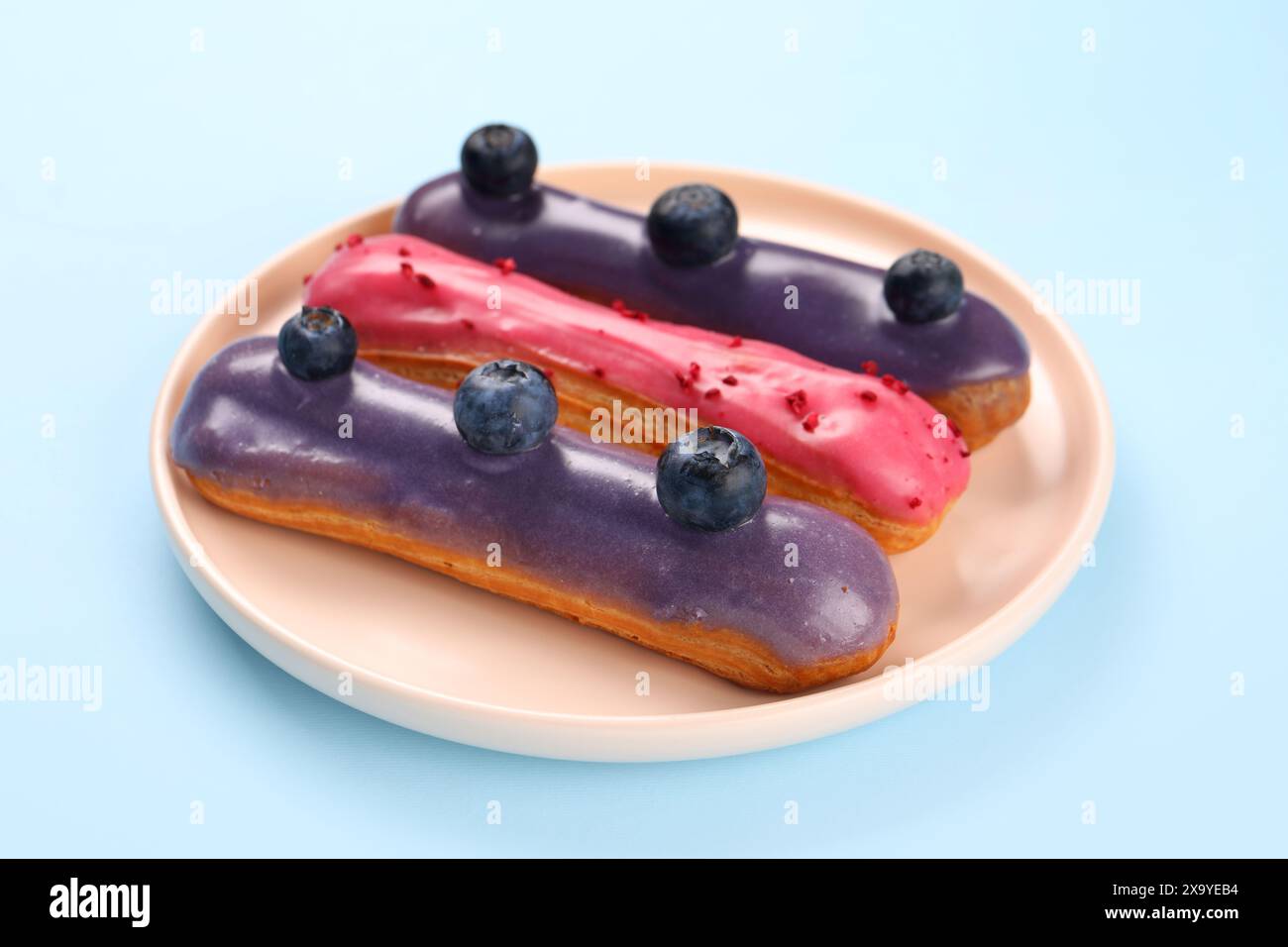 Delicious eclairs covered with glaze on light blue background Stock ...