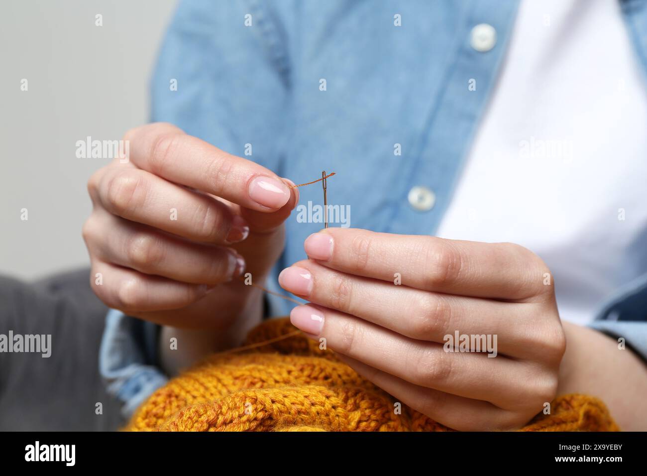 Woman inserting thread through eye of needle, closeup Stock Photo - Alamy
