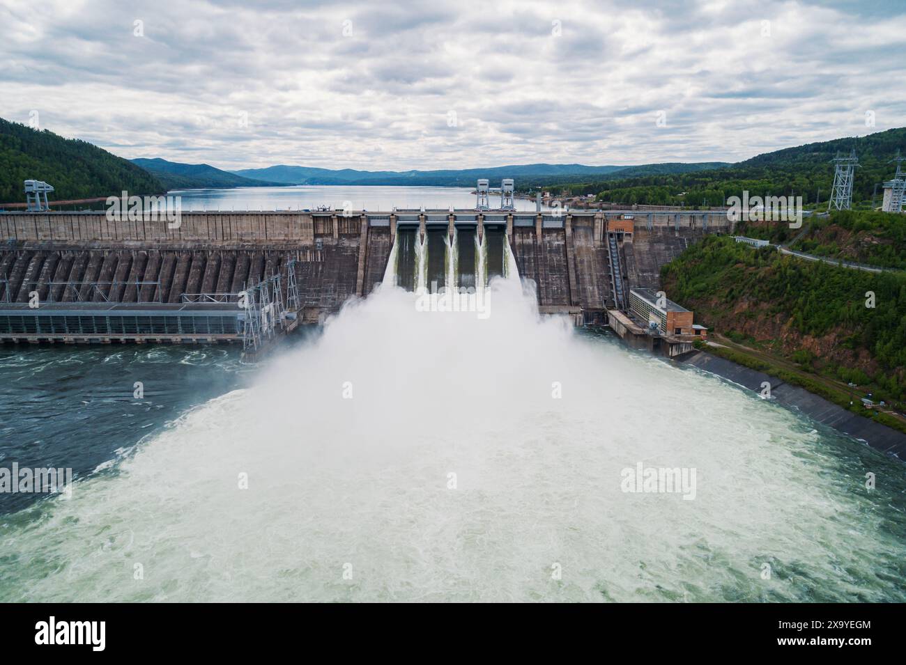 Aerial view of concrete dam releasing water into river on cloudy day ...