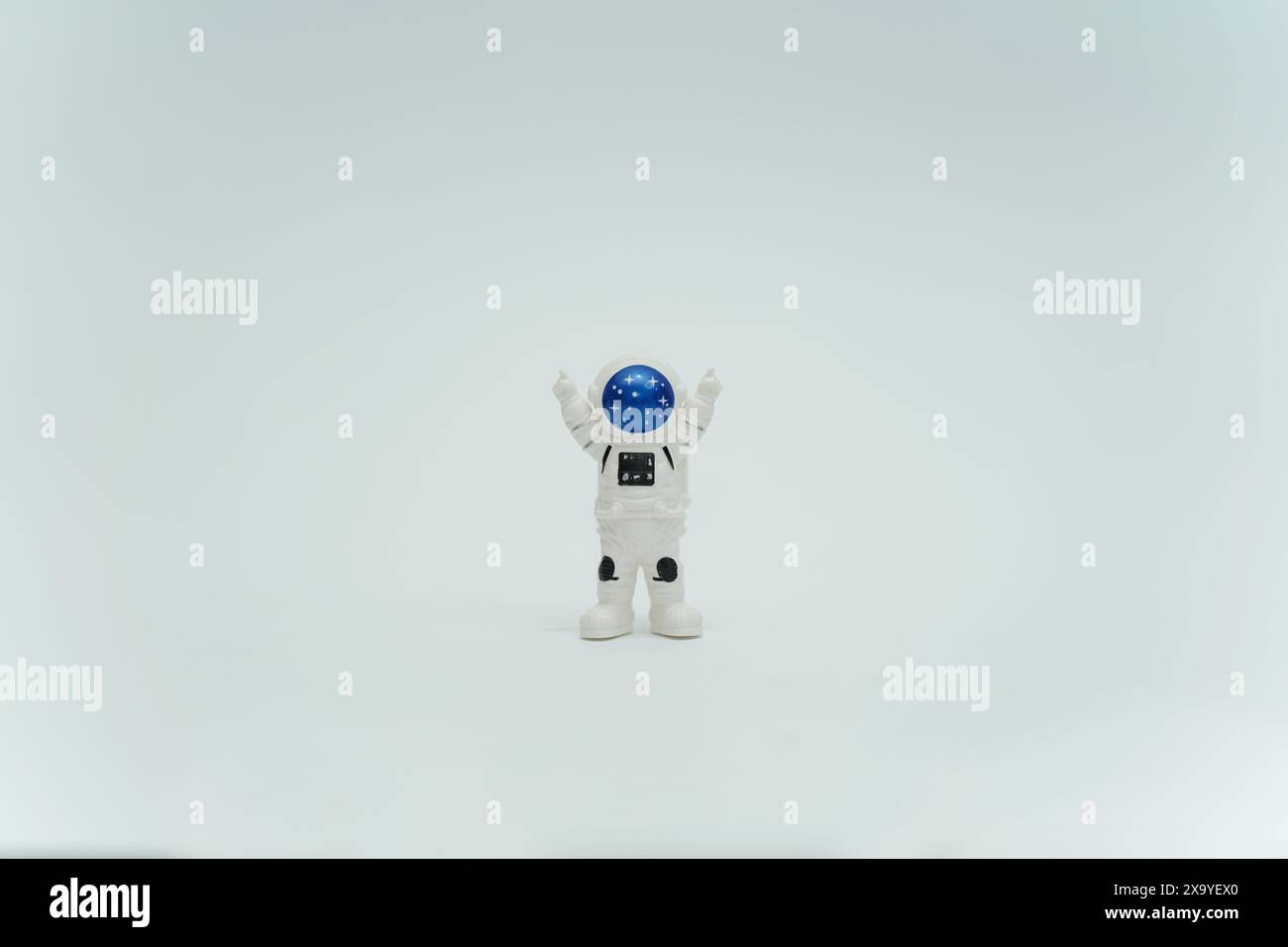 A plastic toy astronaut with raised arms on white background, the ...