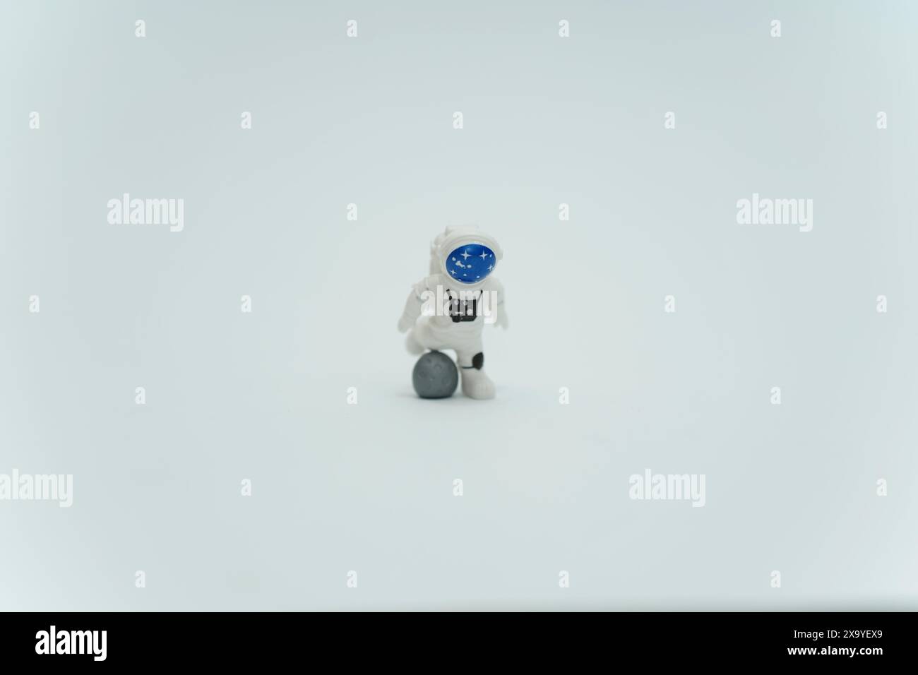 A plastic toy astronaut kicking to the moon on a white background the ...