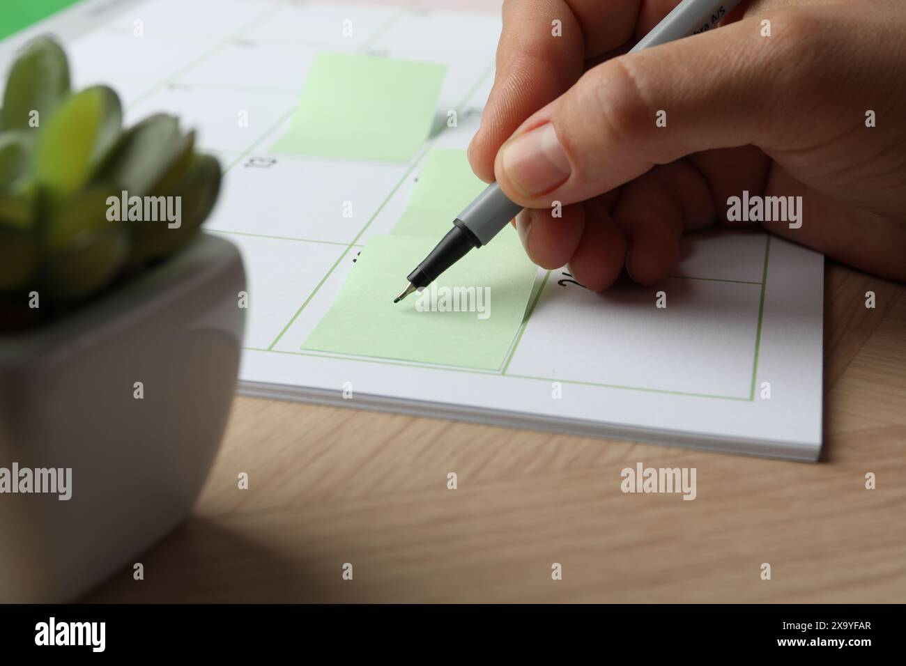 Timetable. Man making schedule using calendar and sticky note at wooden ...