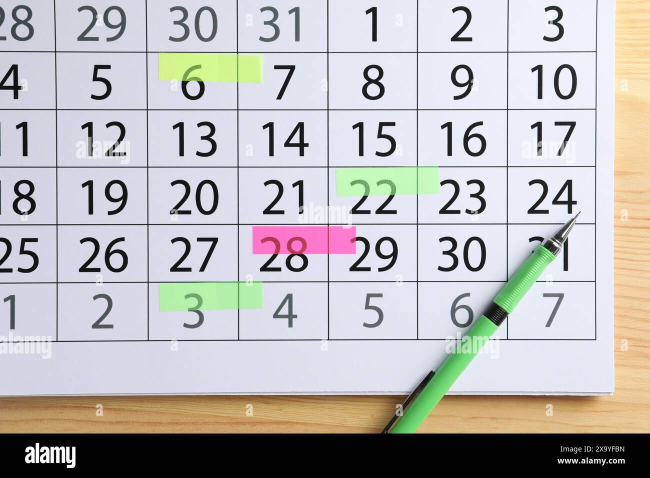 Timetable. Calendar page with marked dates and pen on wooden table, top ...
